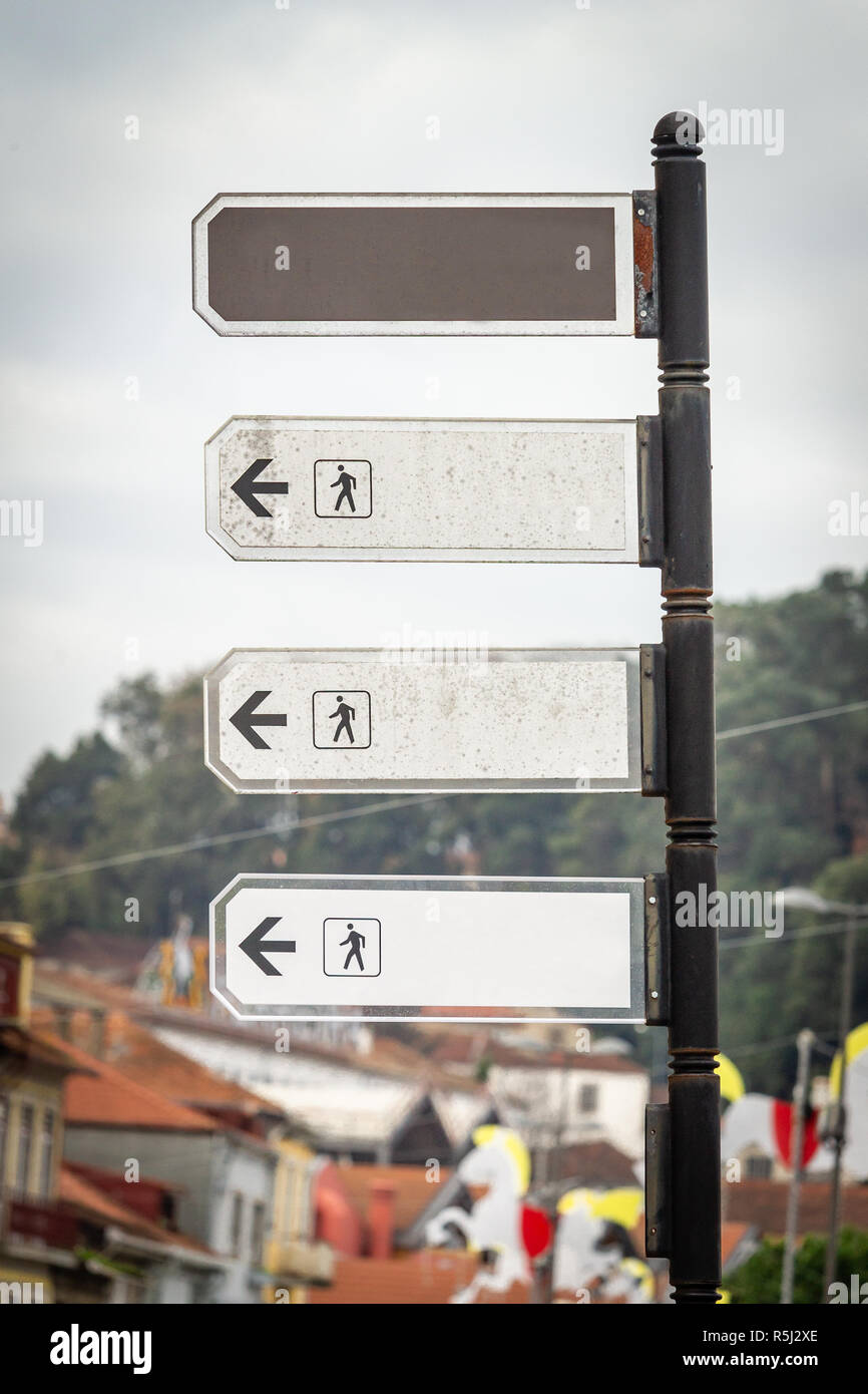 Vertical bronze pole with three empty white direction signs with ...