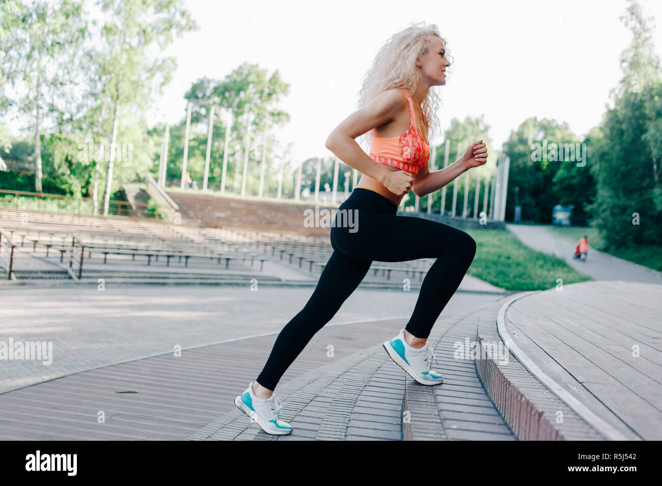 Photo of curly-haired athletic woman running through park among Stock ...