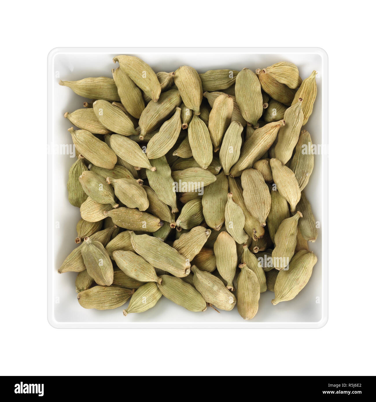 Dried cardamom in square bowl on white background Stock Photo - Alamy