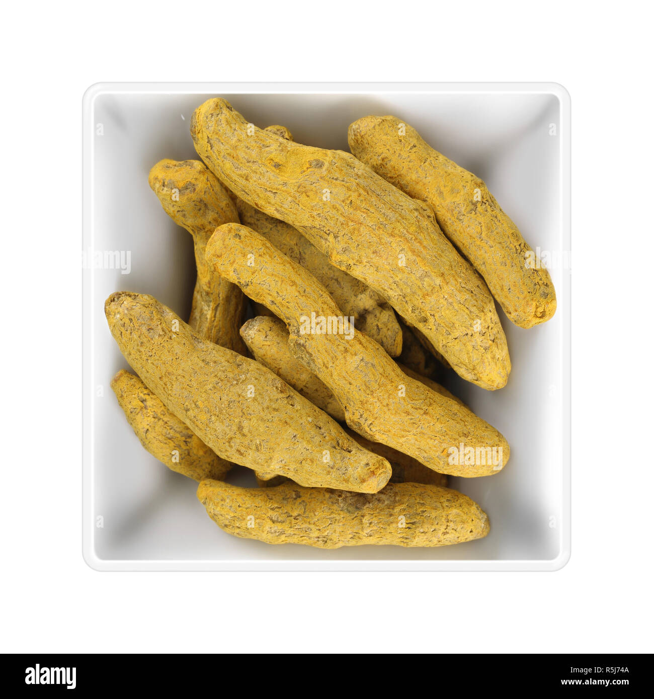 Dried turmeric in square bowl on white background Stock Photo - Alamy