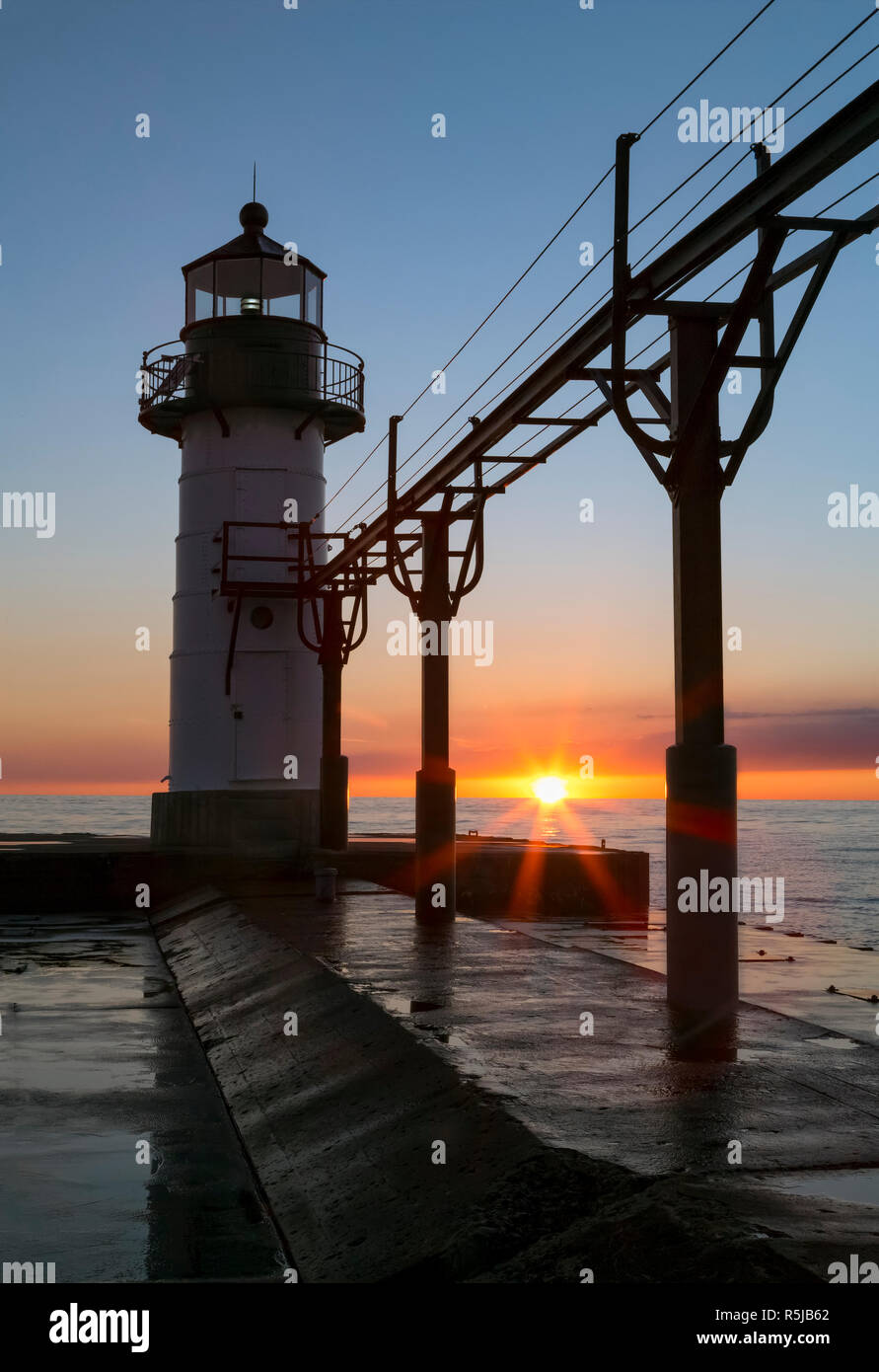 The setting sun silhouettes the North Pier Outer Lighthouse on Lake ...