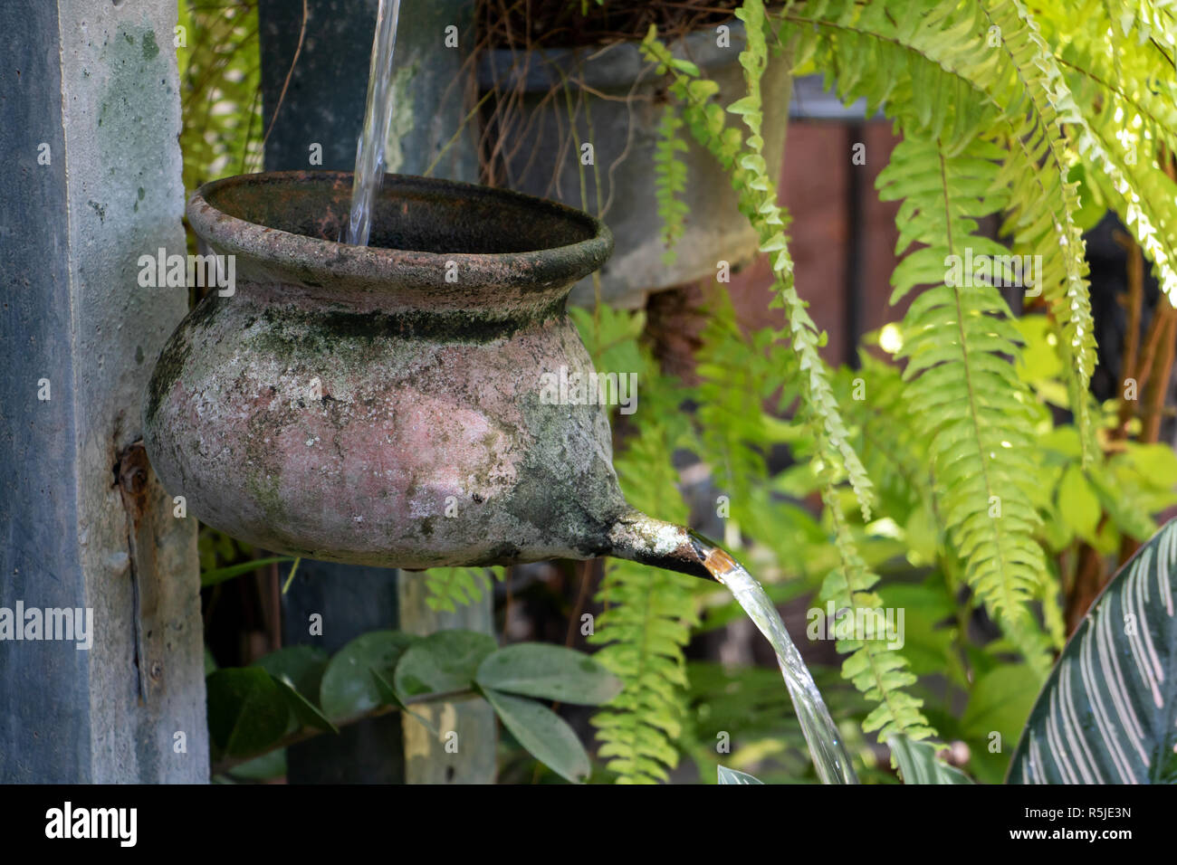 Water cascade from pots on pillar with flowing water in a tropical ...