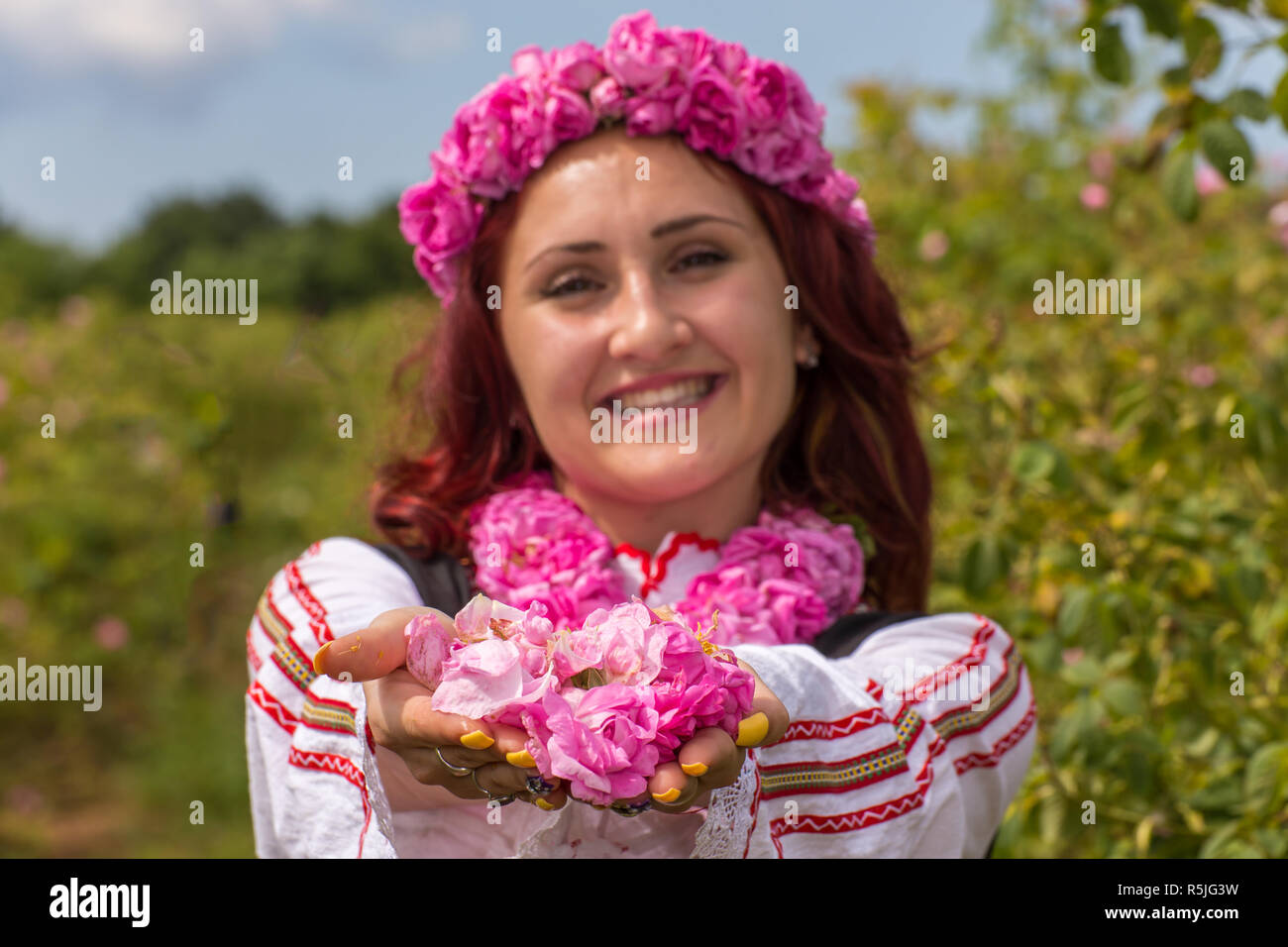 Bulgarian girl dressed in traditional clothes giving roses. Looking ...