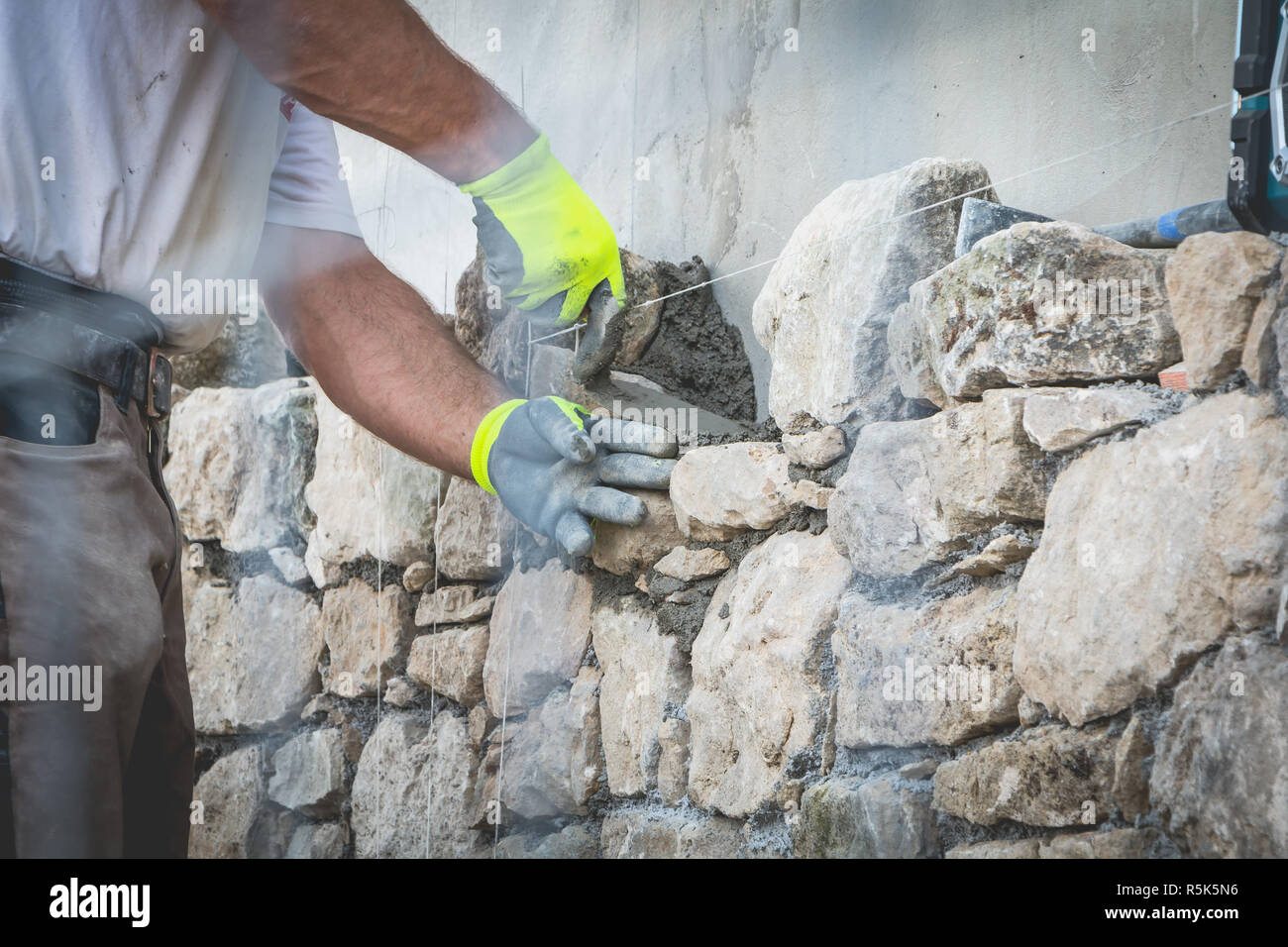 worker rides a stone wall on a traditional renovation site Stock Photo ...