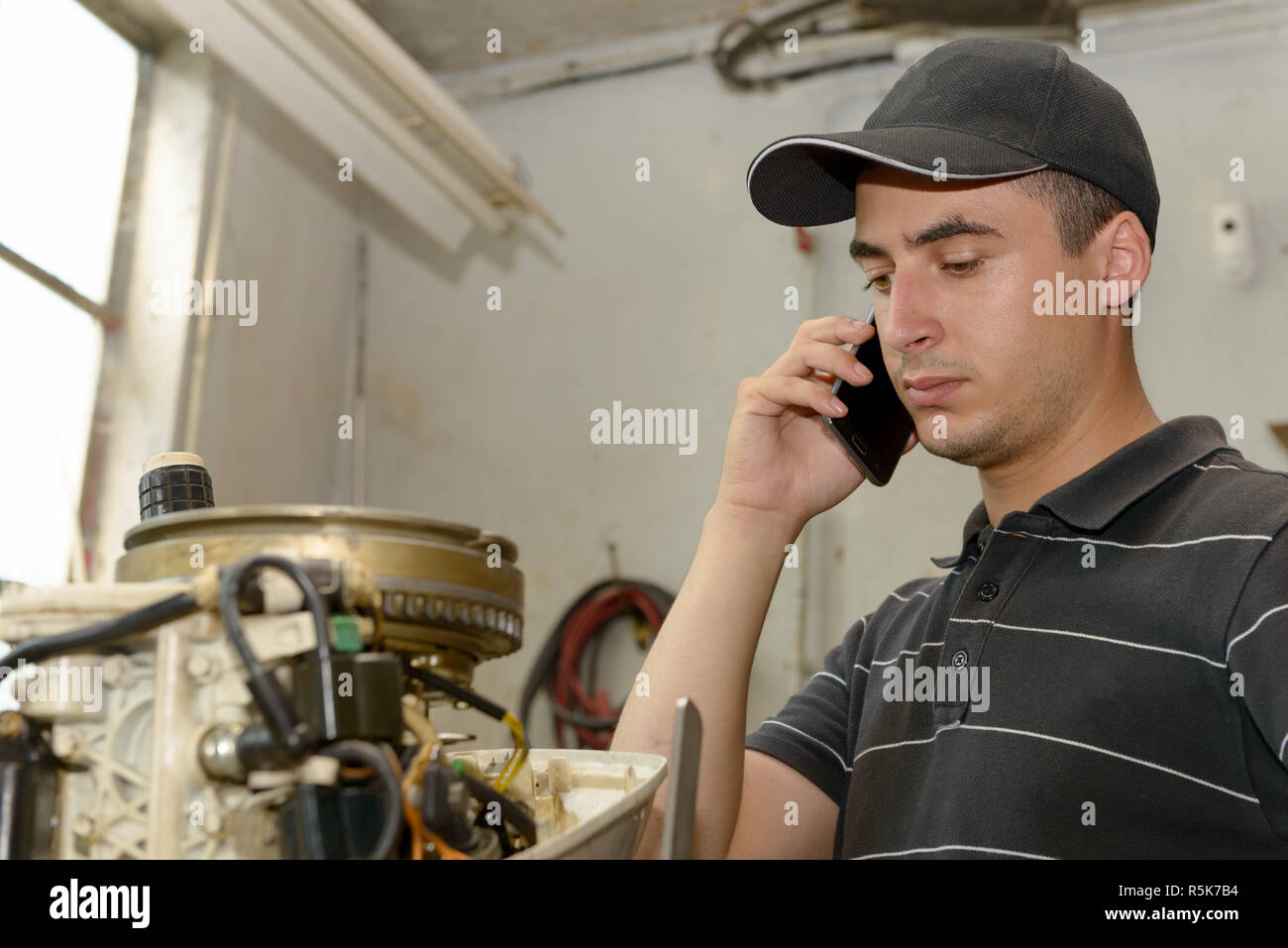 young man mechanic repairing motor boats and phone at customer Stock ...