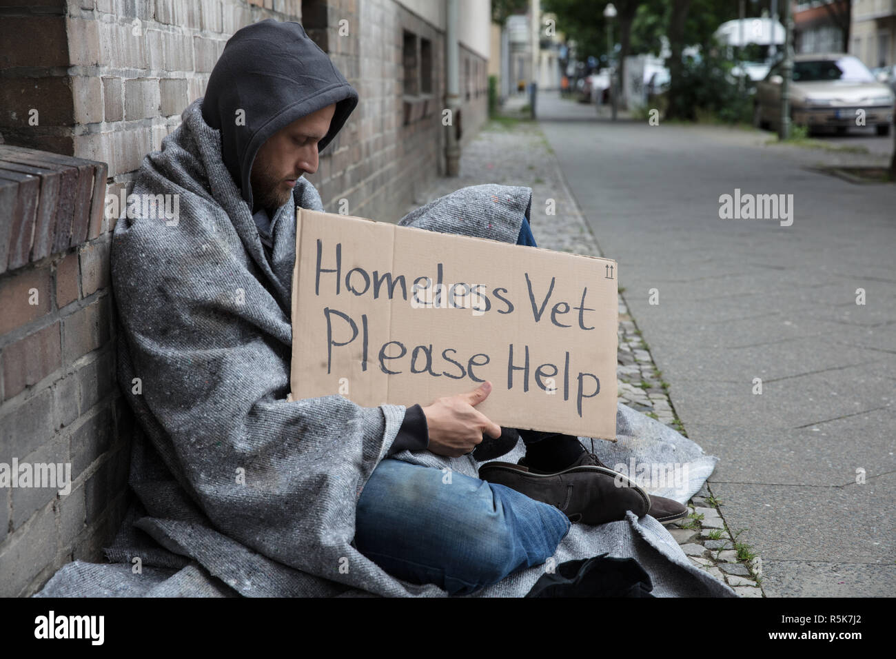 Male Homeless Sitting On A Street Asking For Help Stock Photo - Alamy