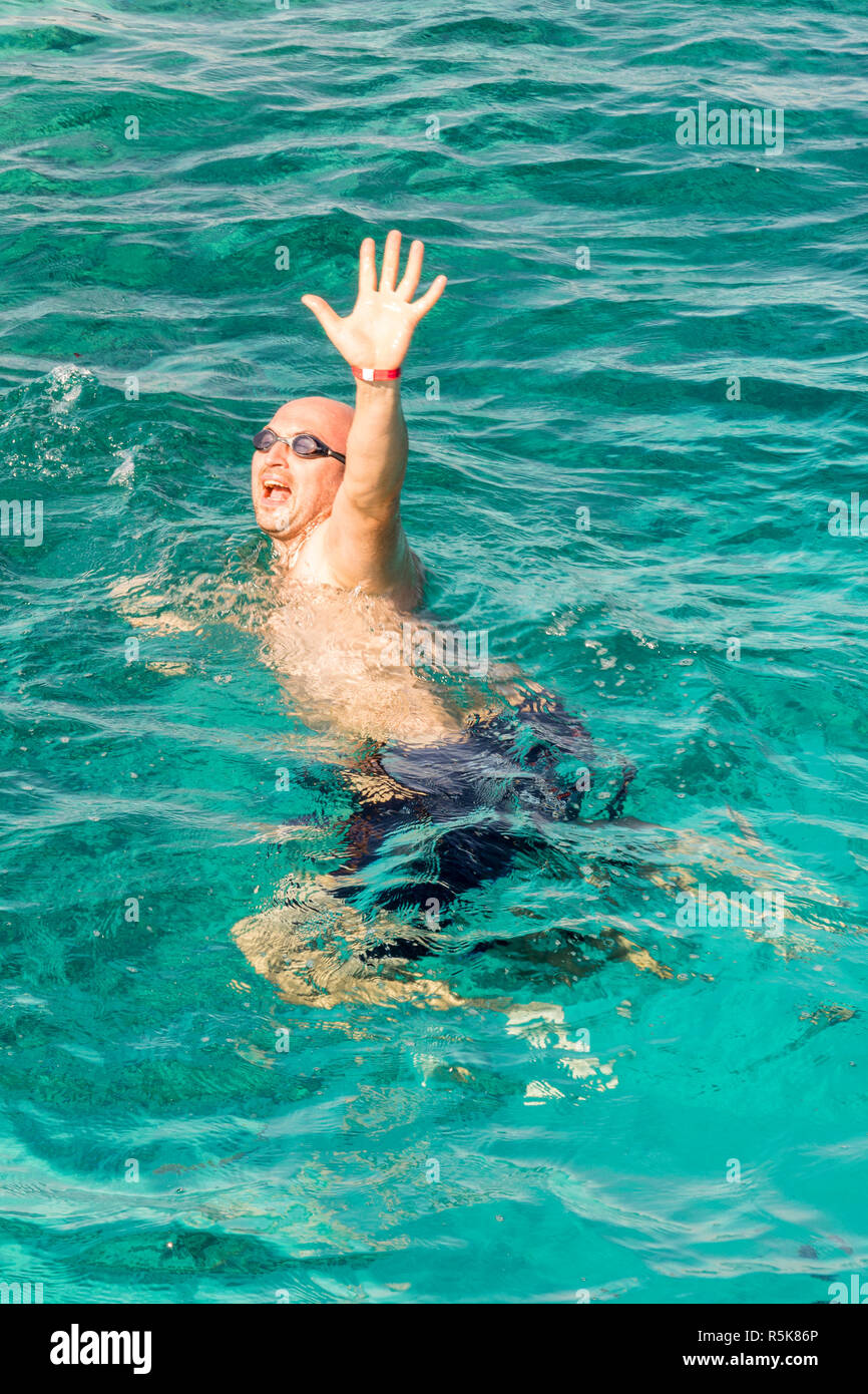 Drowning man in sea asking for help with raised arms. The man is ...