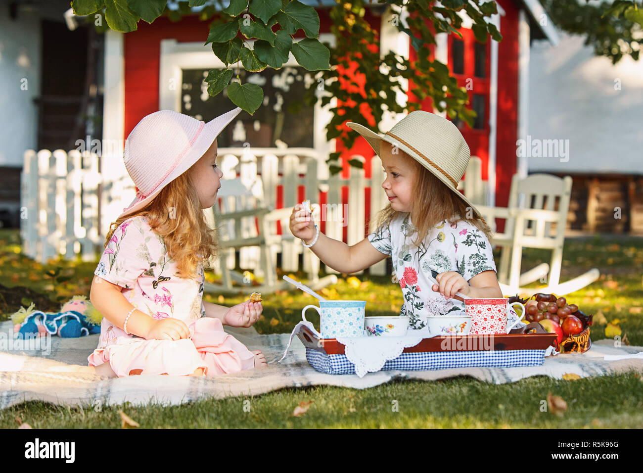 Two little girls sitting on green grass Stock Photo - Alamy