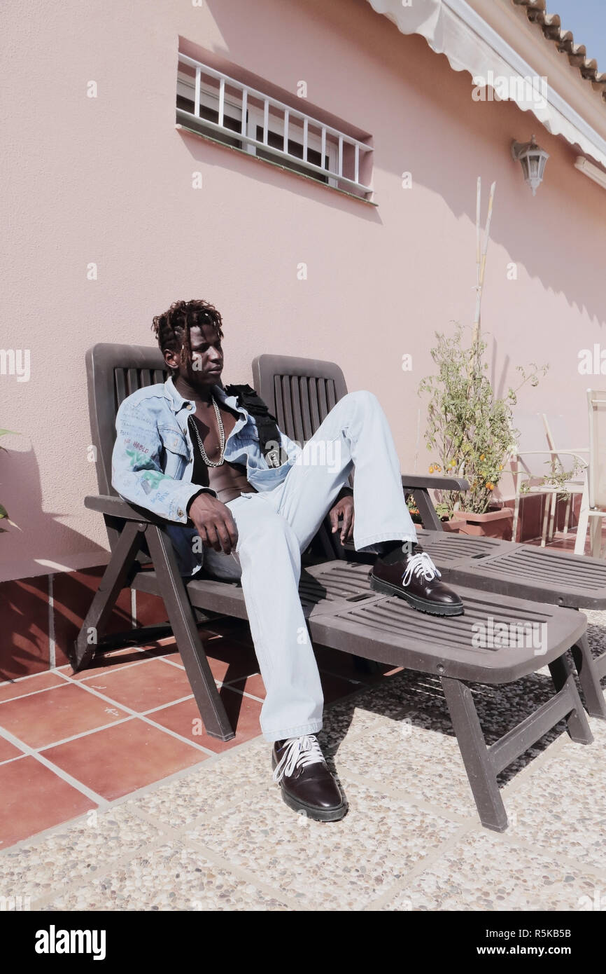 Young black man resting on a lounger Stock Photo - Alamy