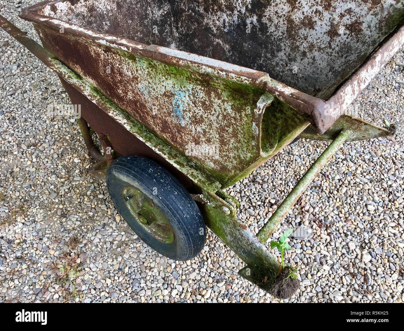 very old and rusty wheelbarrow for garden waste Stock Photo - Alamy
