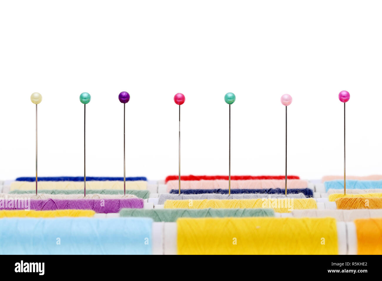 sewing needle and spool of threads on white background Stock Photo - Alamy