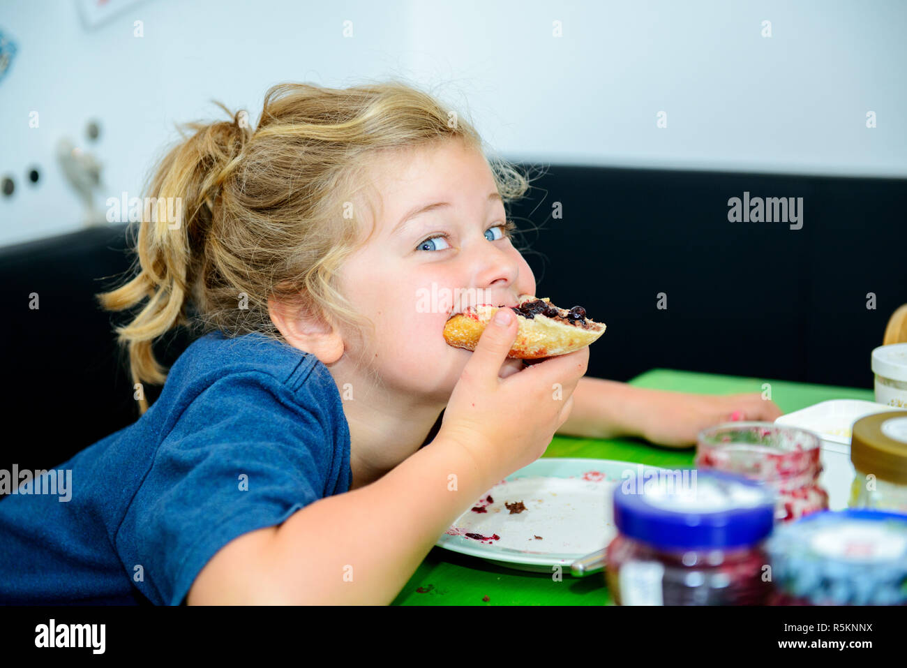 funny girl eating bread roll with jam Stock Photo - Alamy