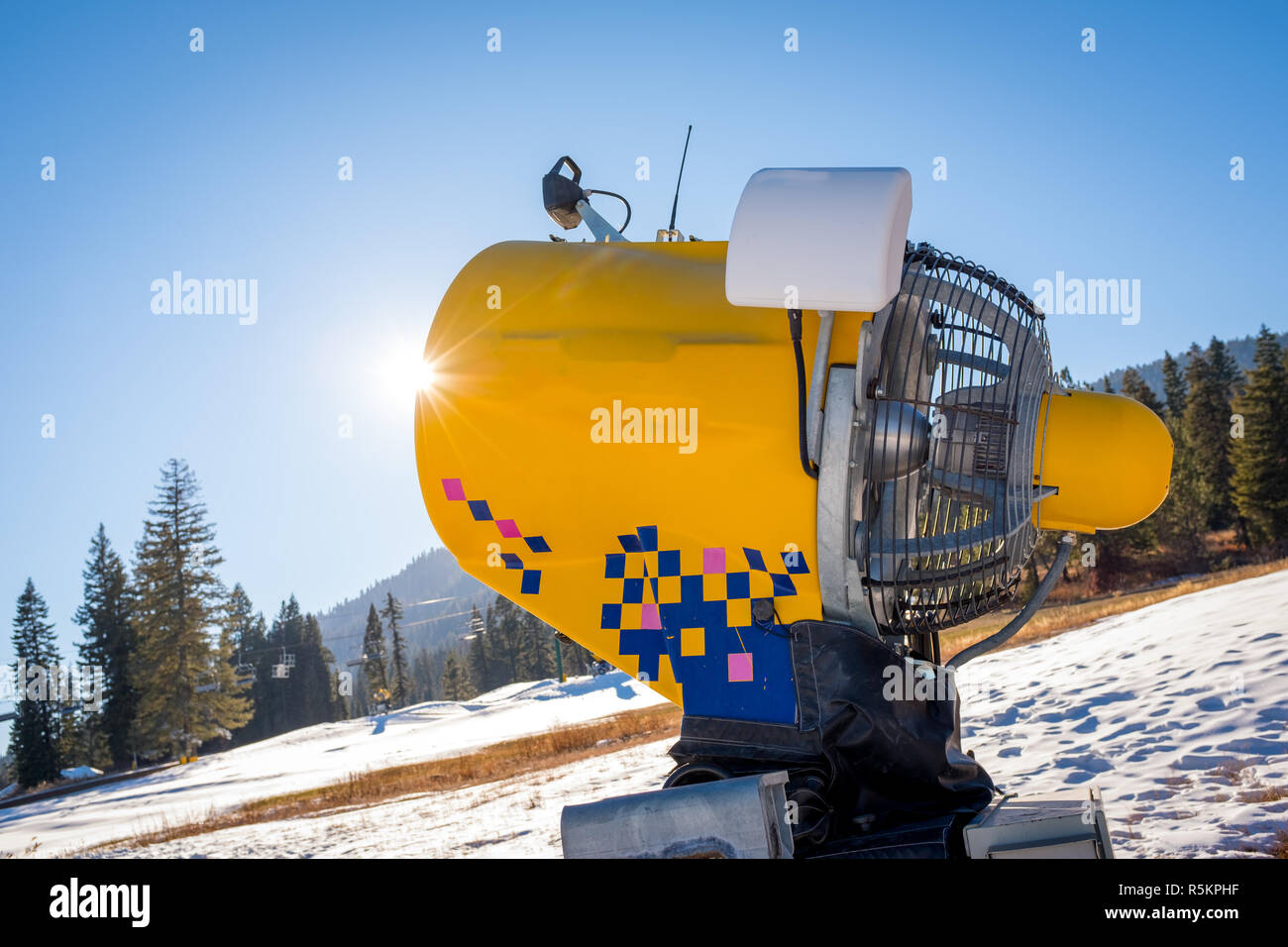 Sun star shines from behind a yellow machine that makes snow Stock ...