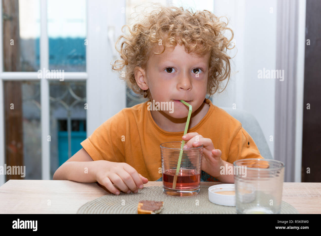 Cute little boy is drinking red juice using straw Stock Photo - Alamy