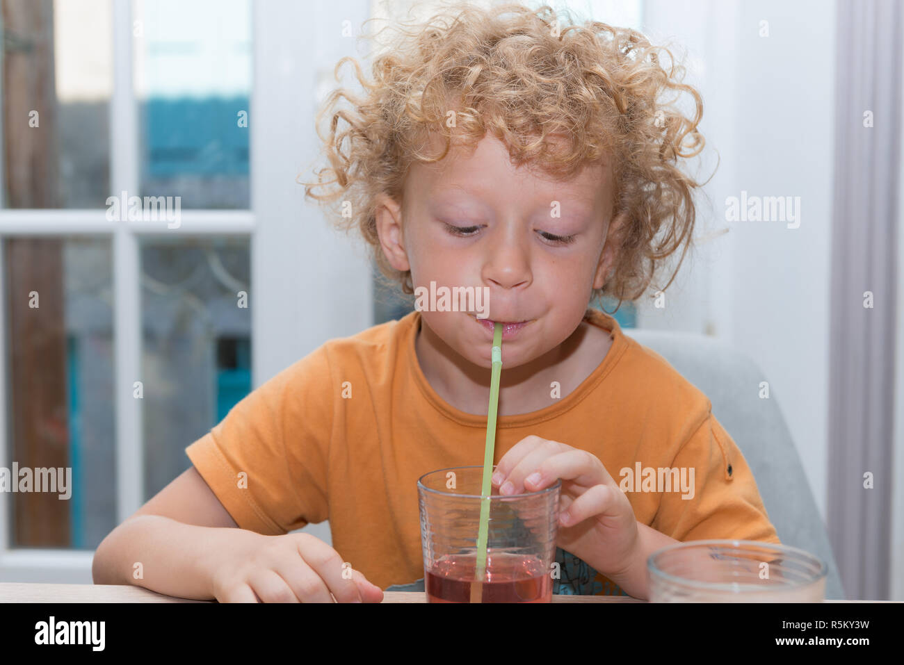Cute little boy is drinking red juice using straw Stock Photo - Alamy