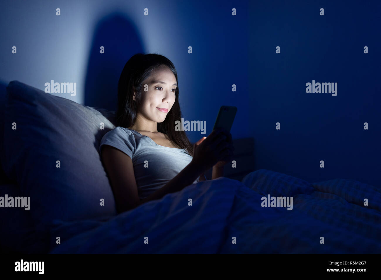 Woman use of mobile phone on bed at night Stock Photo - Alamy