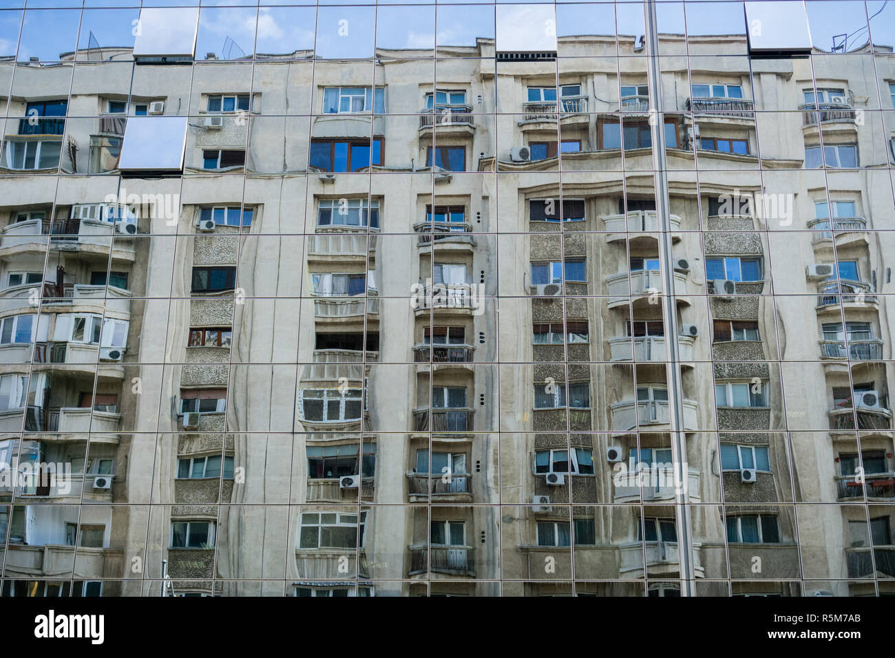 Distorted view of apartment building reflected in the glass facade of ...