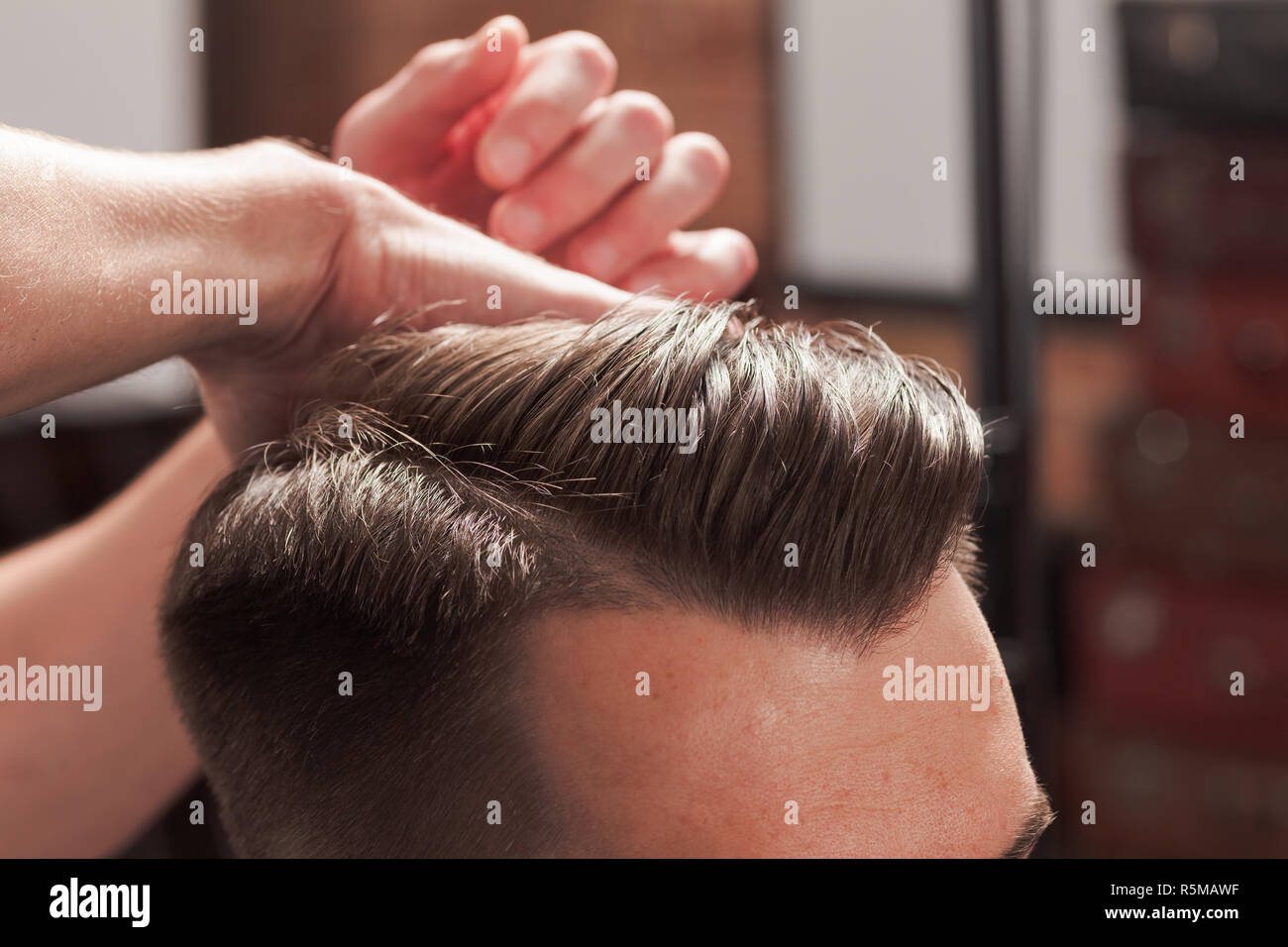 The hands of barber making haircut to young man in barbershop Stock ...