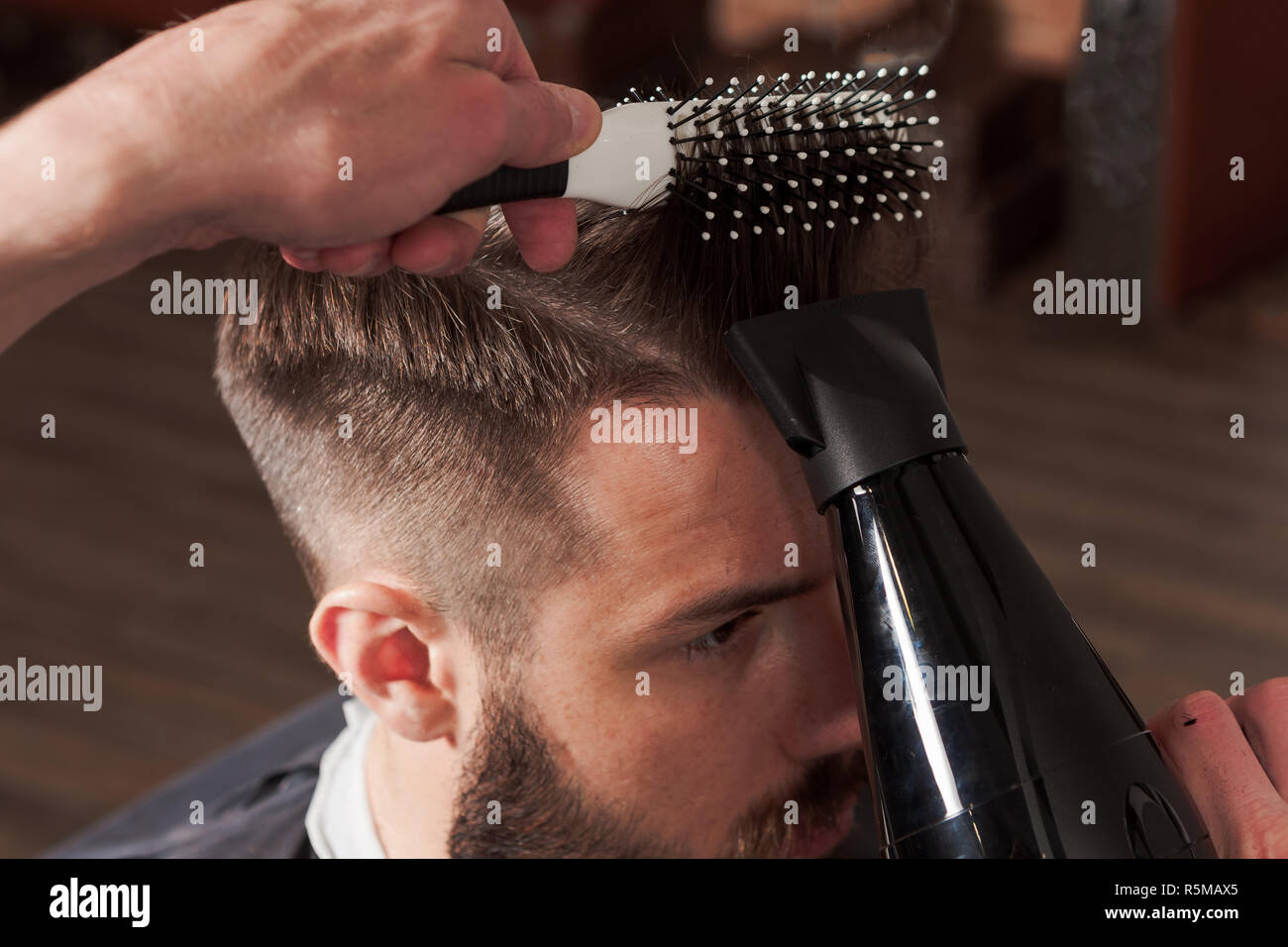 The hands of barber making haircut to young man in barbershop Stock ...