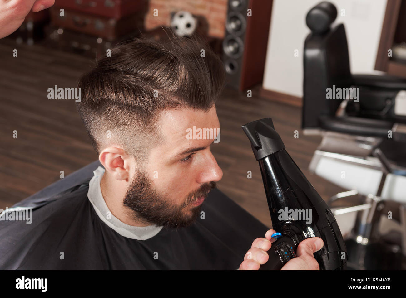 The hands of barber making haircut to young man in barbershop Stock ...