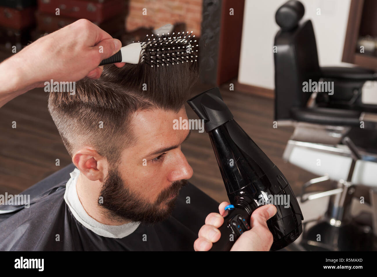 The hands of barber making haircut to young man in barbershop Stock ...
