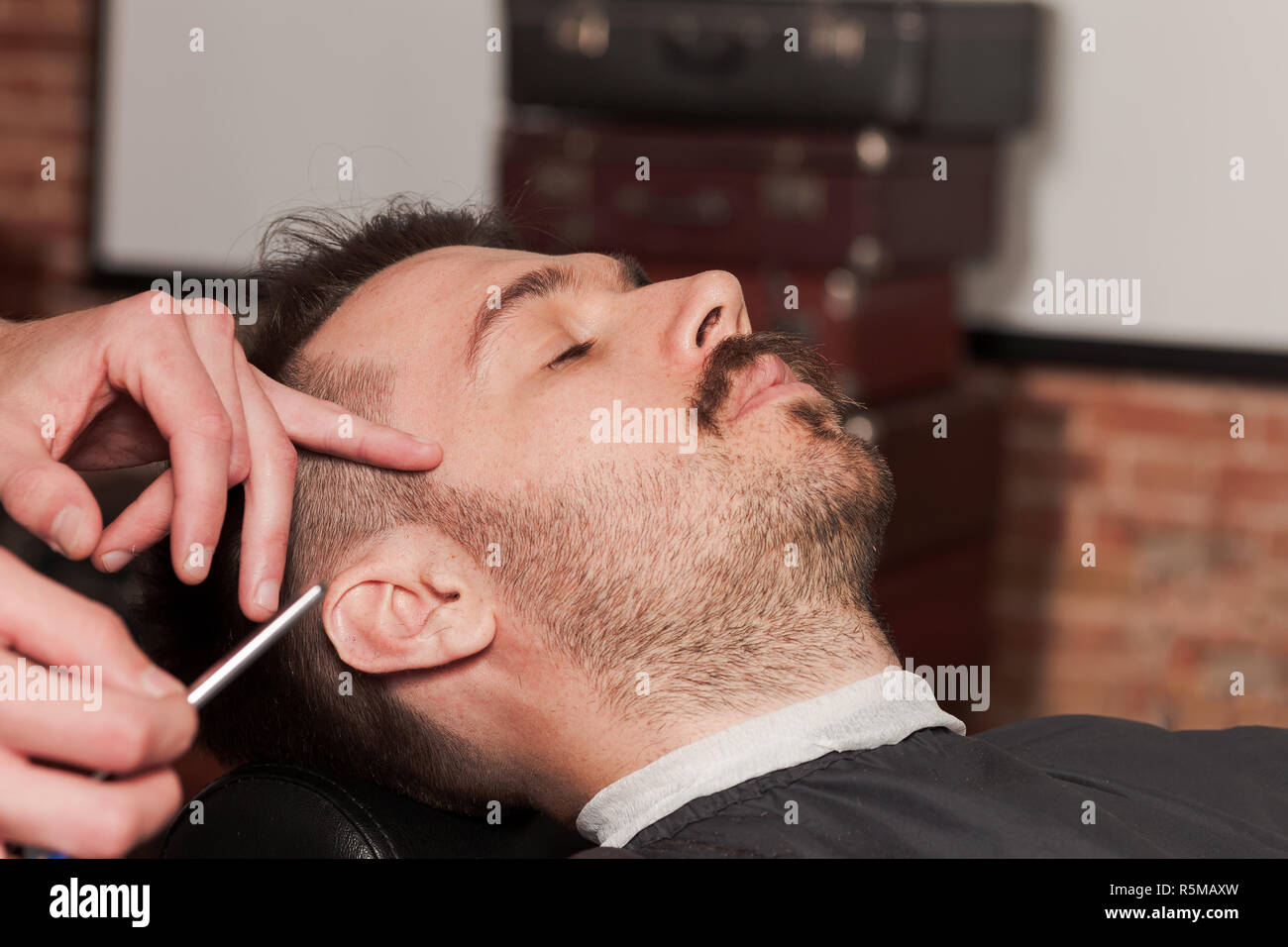 The hands of barber making haircut to young man in barbershop Stock ...