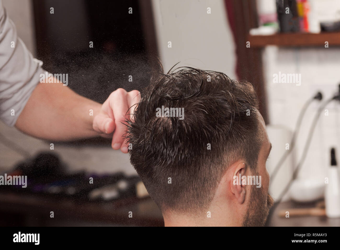 The hands of barber making haircut to young man in barbershop Stock ...