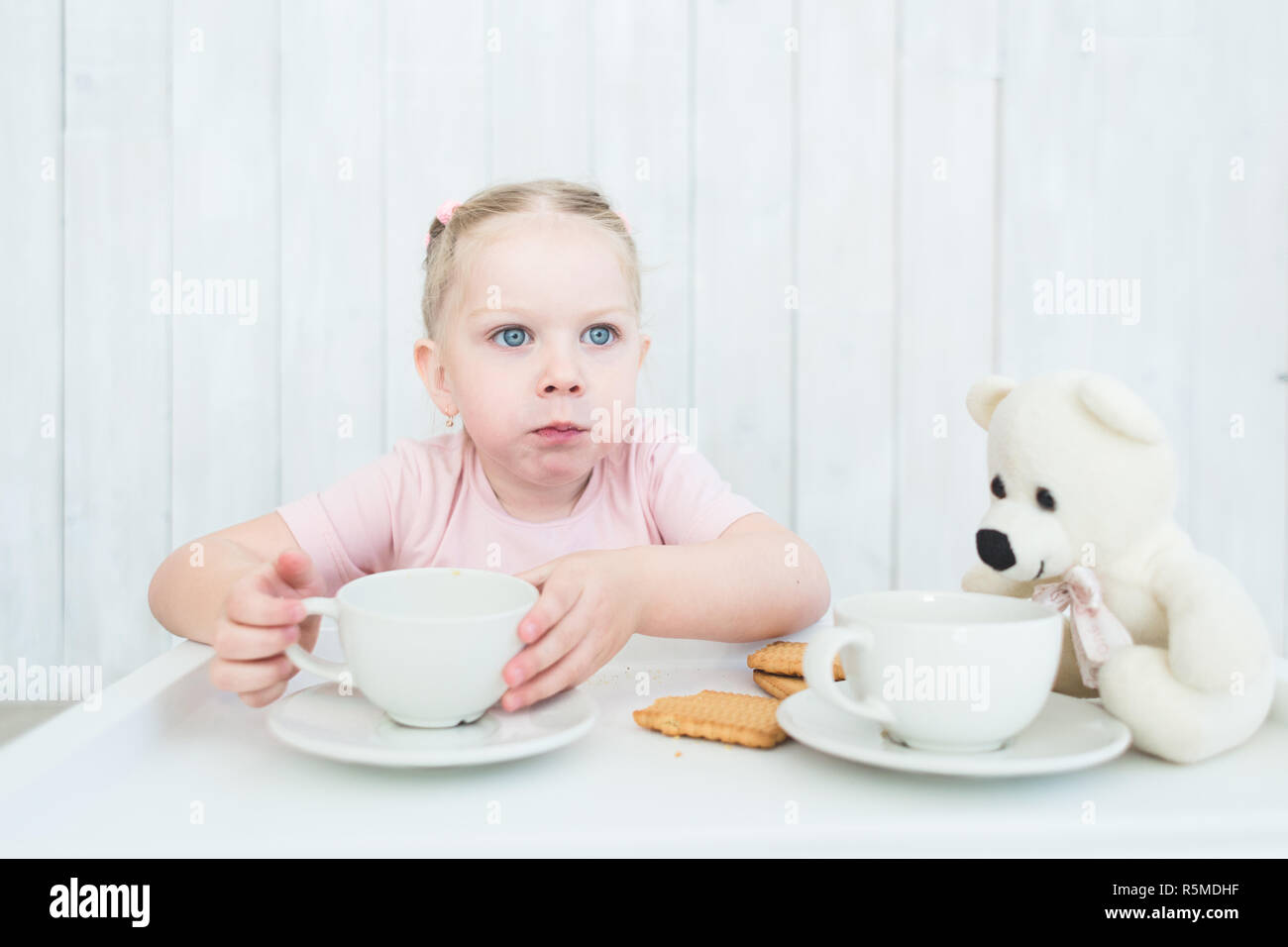 Cute little girl drinks tea with her teddy bear Stock Photo - Alamy