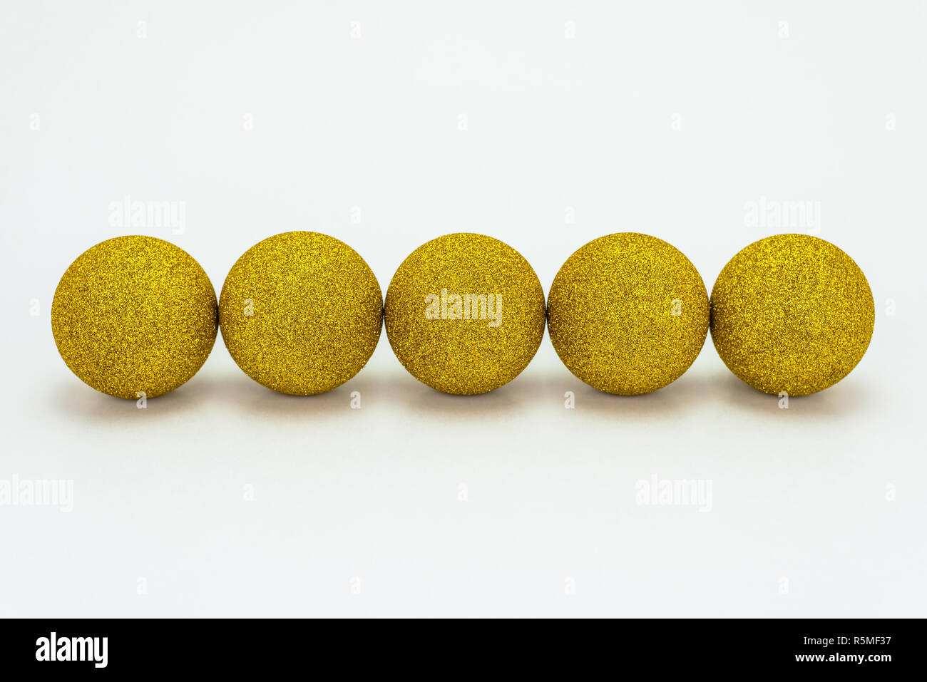Five yellow Christmas baubles, lies in a row isolated on a white ...