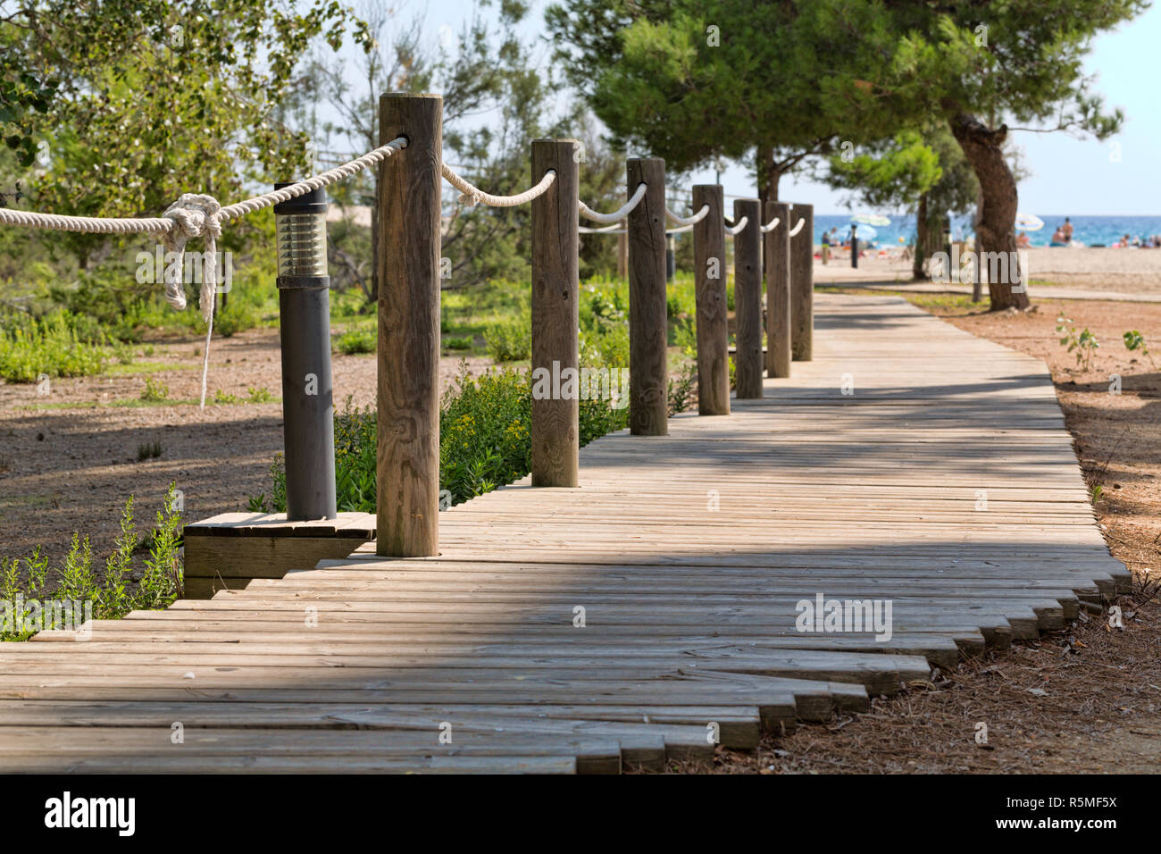 paved trail with wooden rope handrail leading to beautiful ocean beach ...