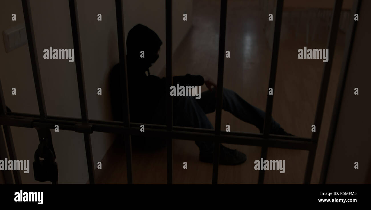 The prisoner behind the bars.Hold with hands on the grids in ...