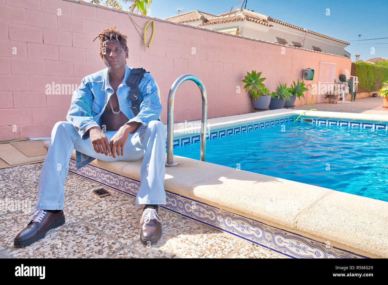 Very attractive black guy sitting on the edge of a pool Stock Photo - Alamy