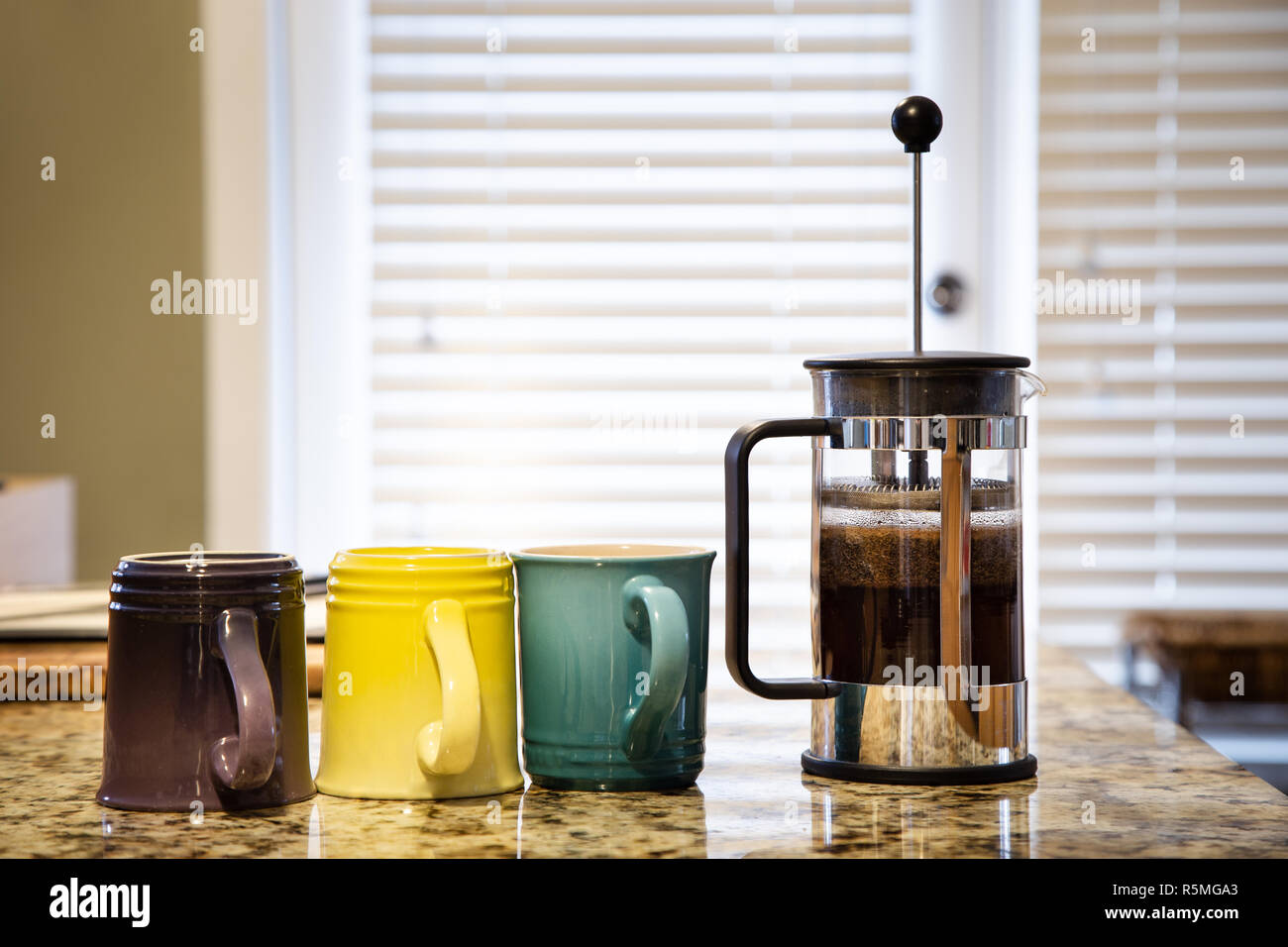 A french press on a kitchen counter top with coffee brewing and multi ...