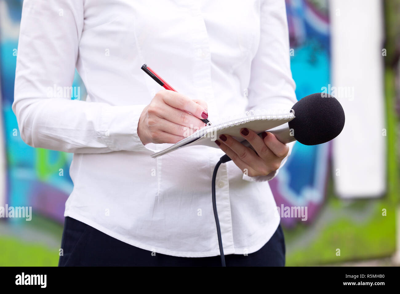 Female journalist at press conference, writing notes, holding ...