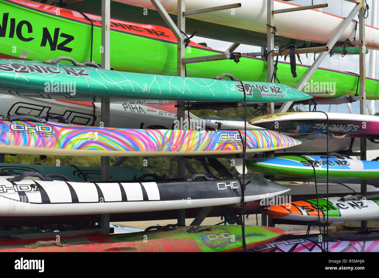 Colorful paddle boards and fiberglass kayaks tightly packed in metal ...