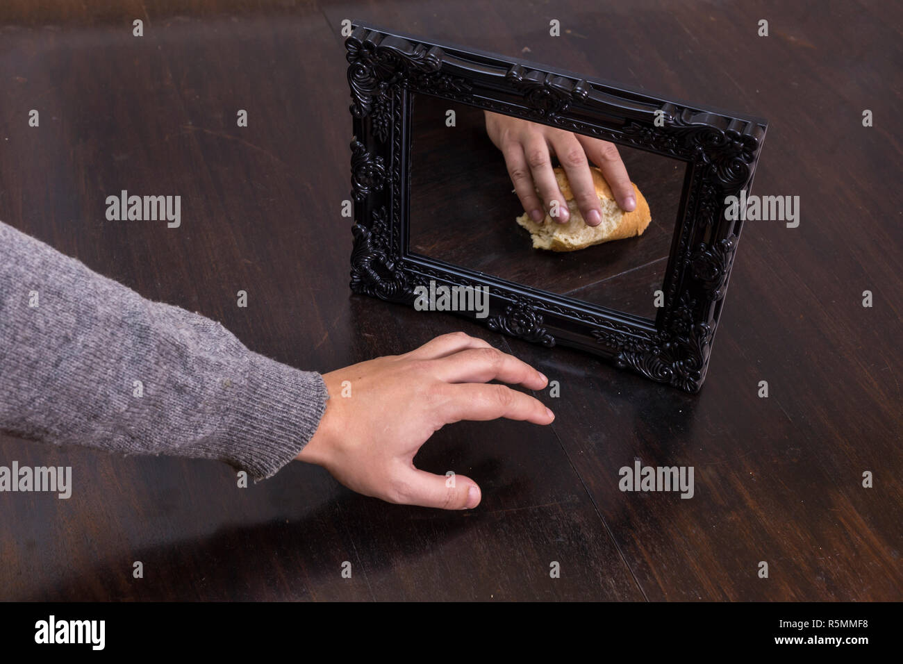 Human hand taking bread from a worn out table. Poverty concept. No ...