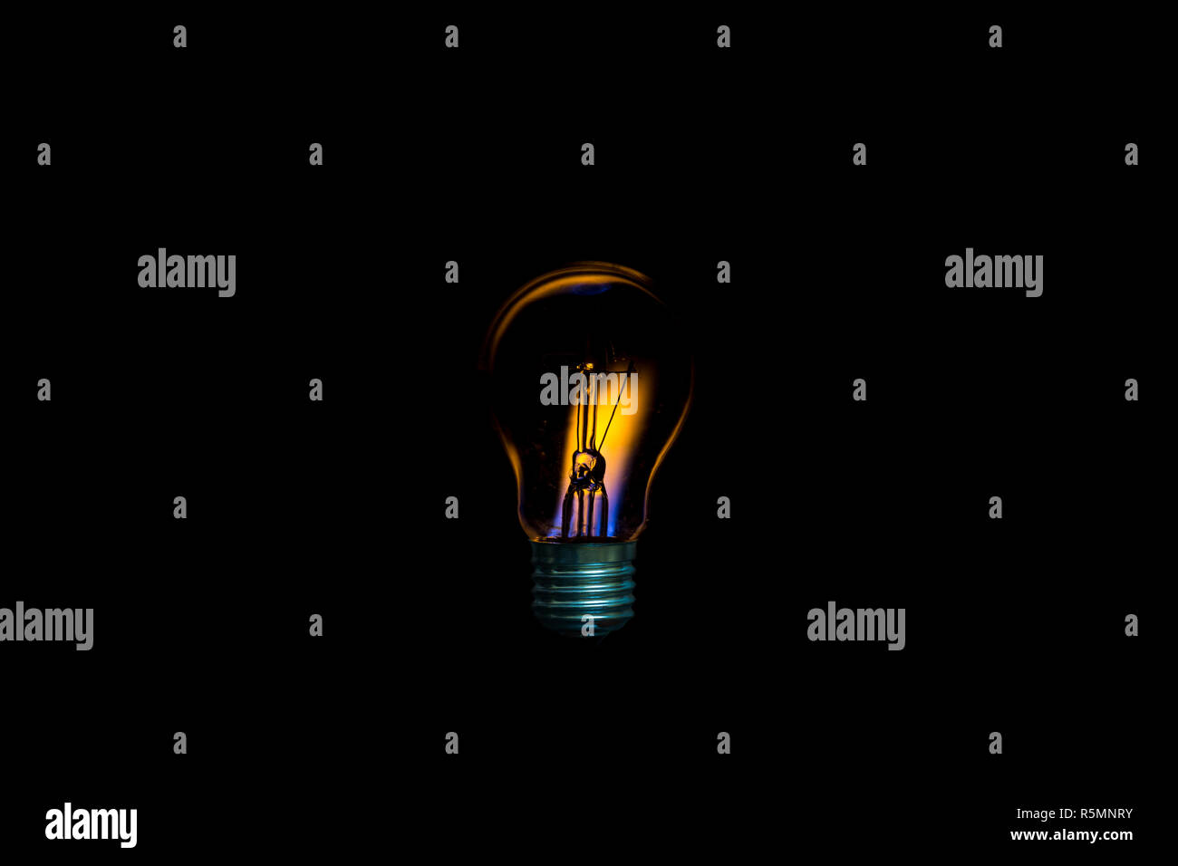 Tungsten light bulb burning like a candle isolated on black background ...