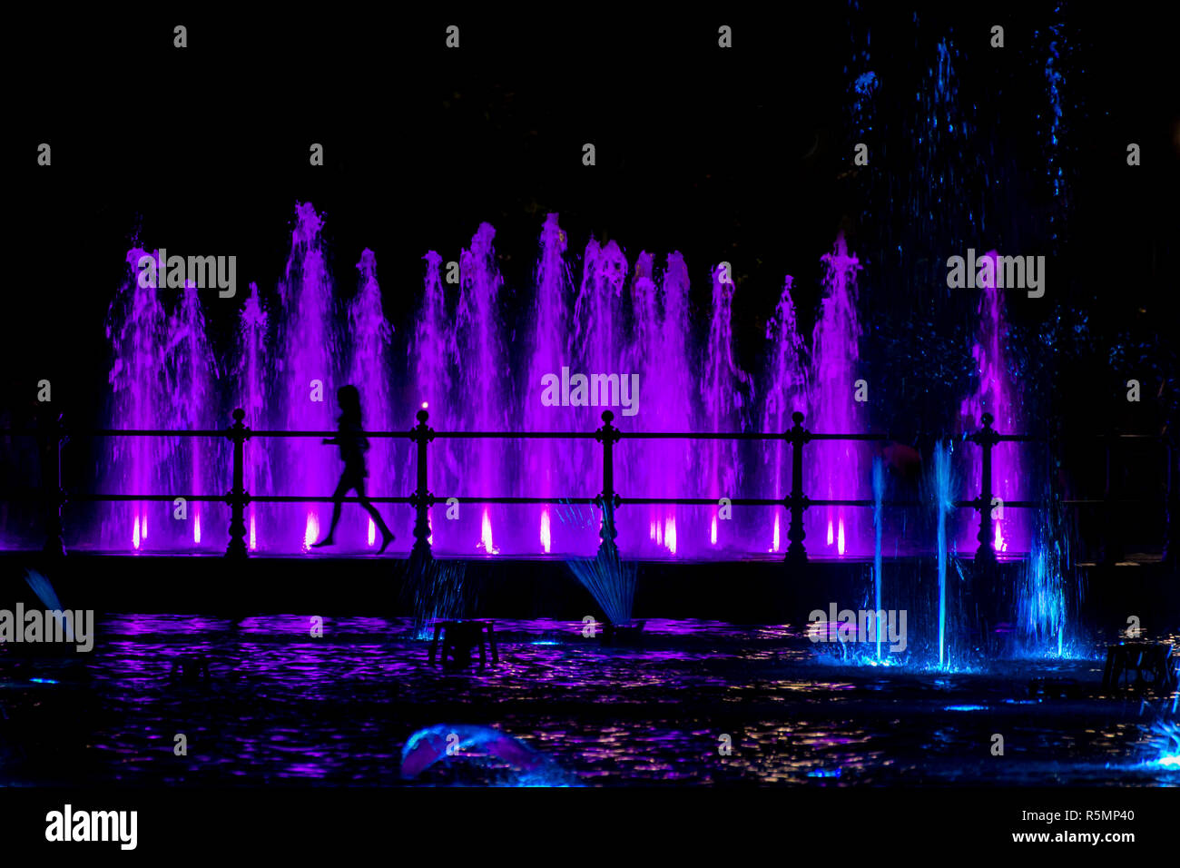 Silhouette of a child running through colorfully lit fountain Stock ...