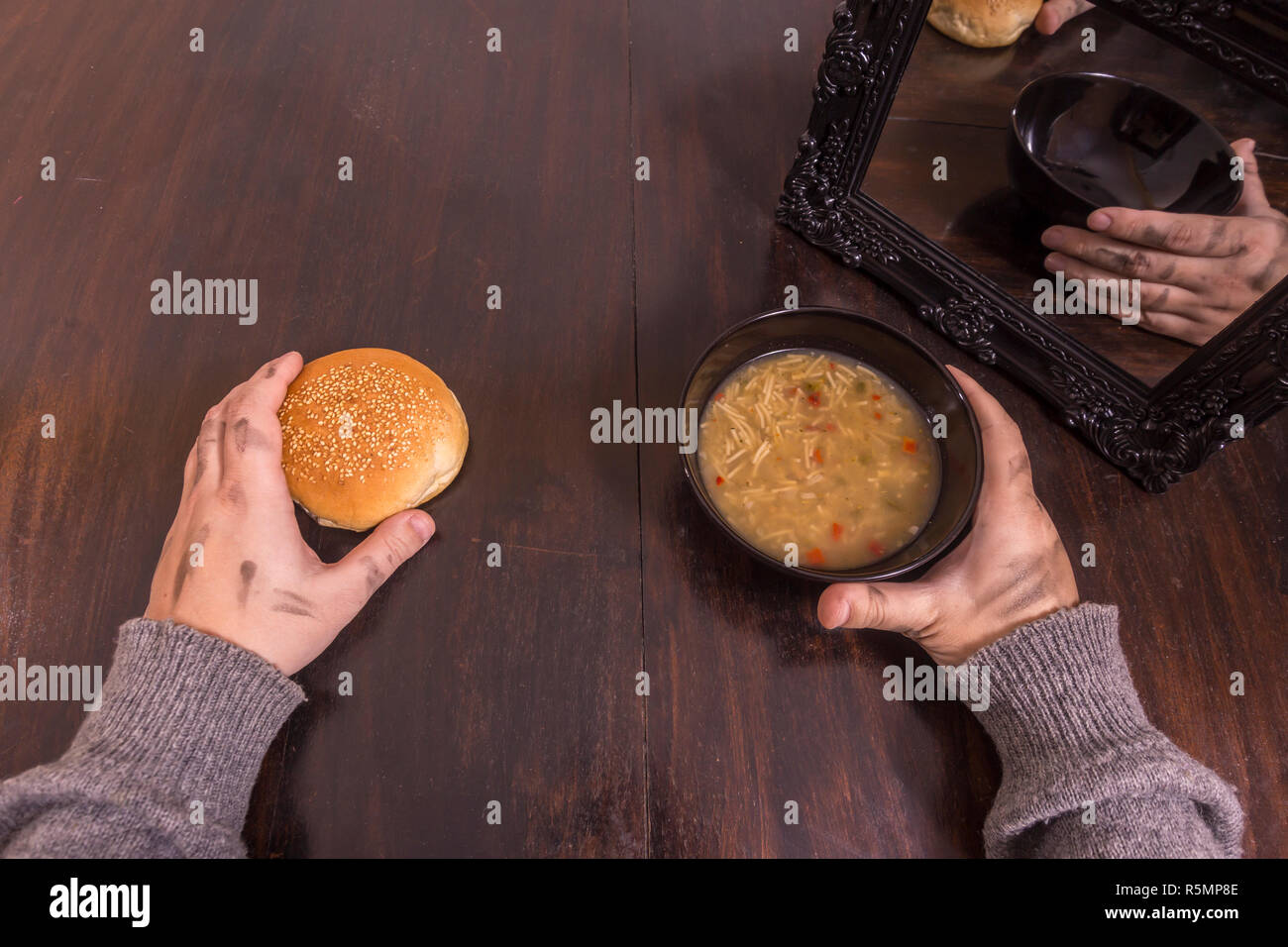 Person with dirty hands taking a bowl of soup from a worn out table ...
