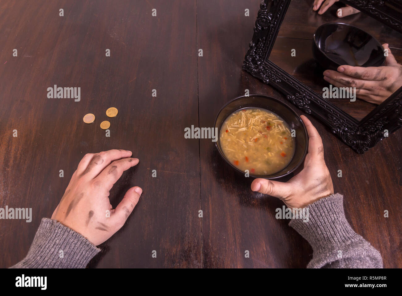 Hands taking a bowl of soup from a worn out table. Poverty and illusion ...