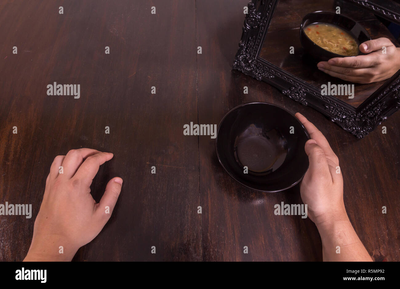 Hands taking a bowl of soup from a worn out table. Poverty and illusion ...