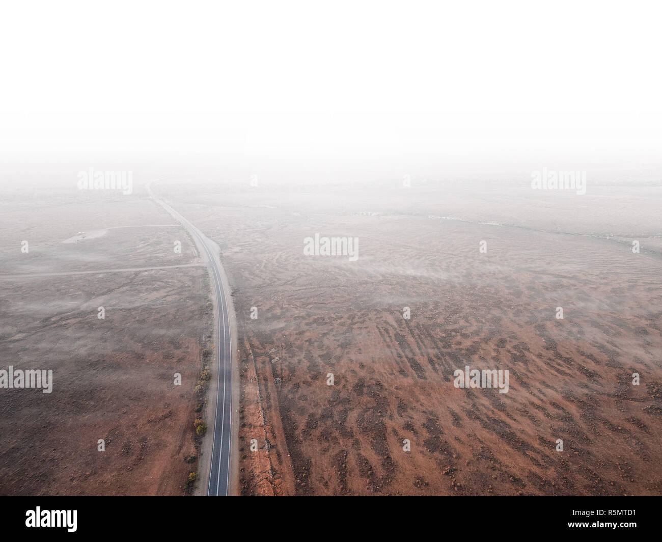 Aerial view of road passing through red desert land and disappearing in ...