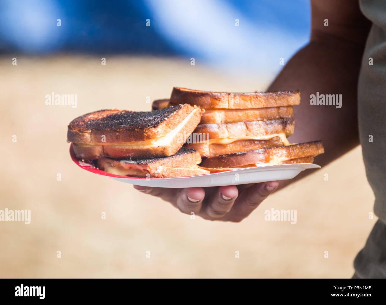 Stacks of grilled cheese sandwiches on a paper plate. Overweight man ...