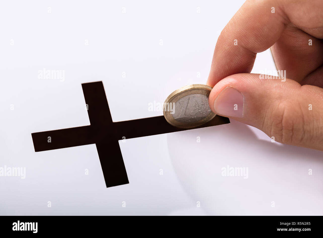 Hand Inserting Coin In Crucifix Slot Stock Photo - Alamy