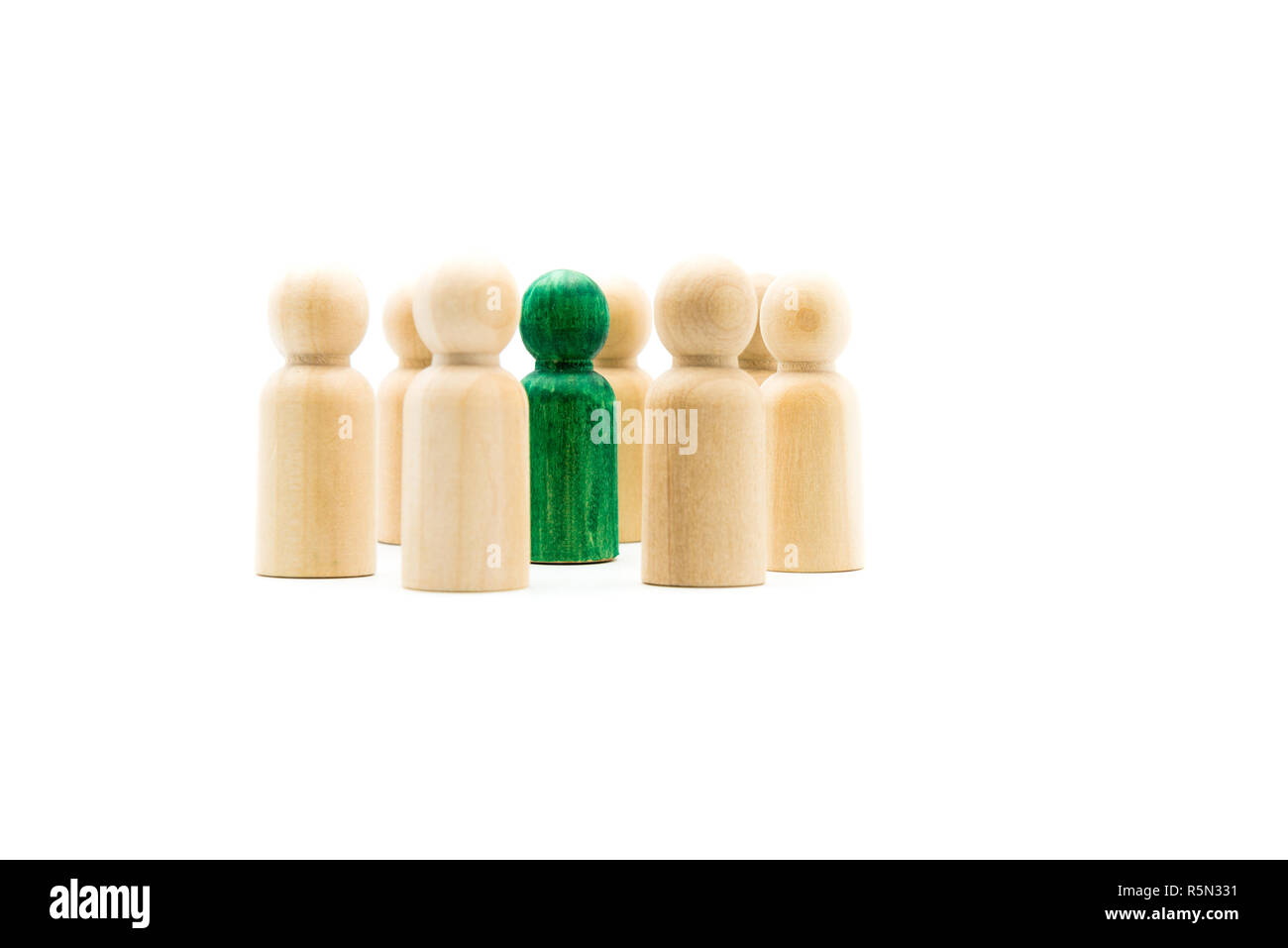 Green figure standing out from the crowd inside circle of wooden ...
