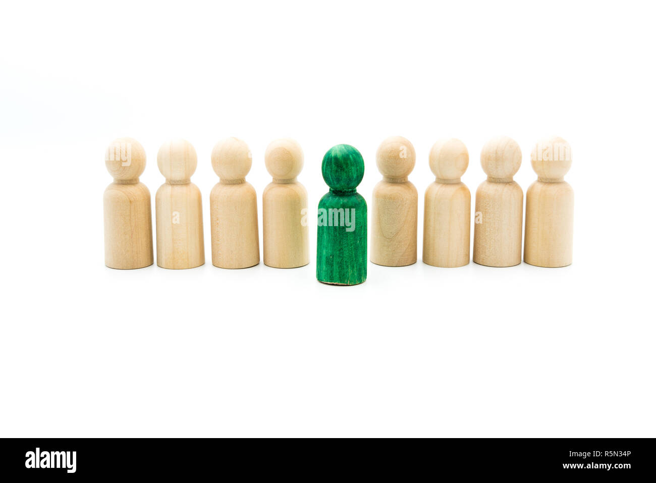 Wooden figures in line as business team, with one green figure standing ...