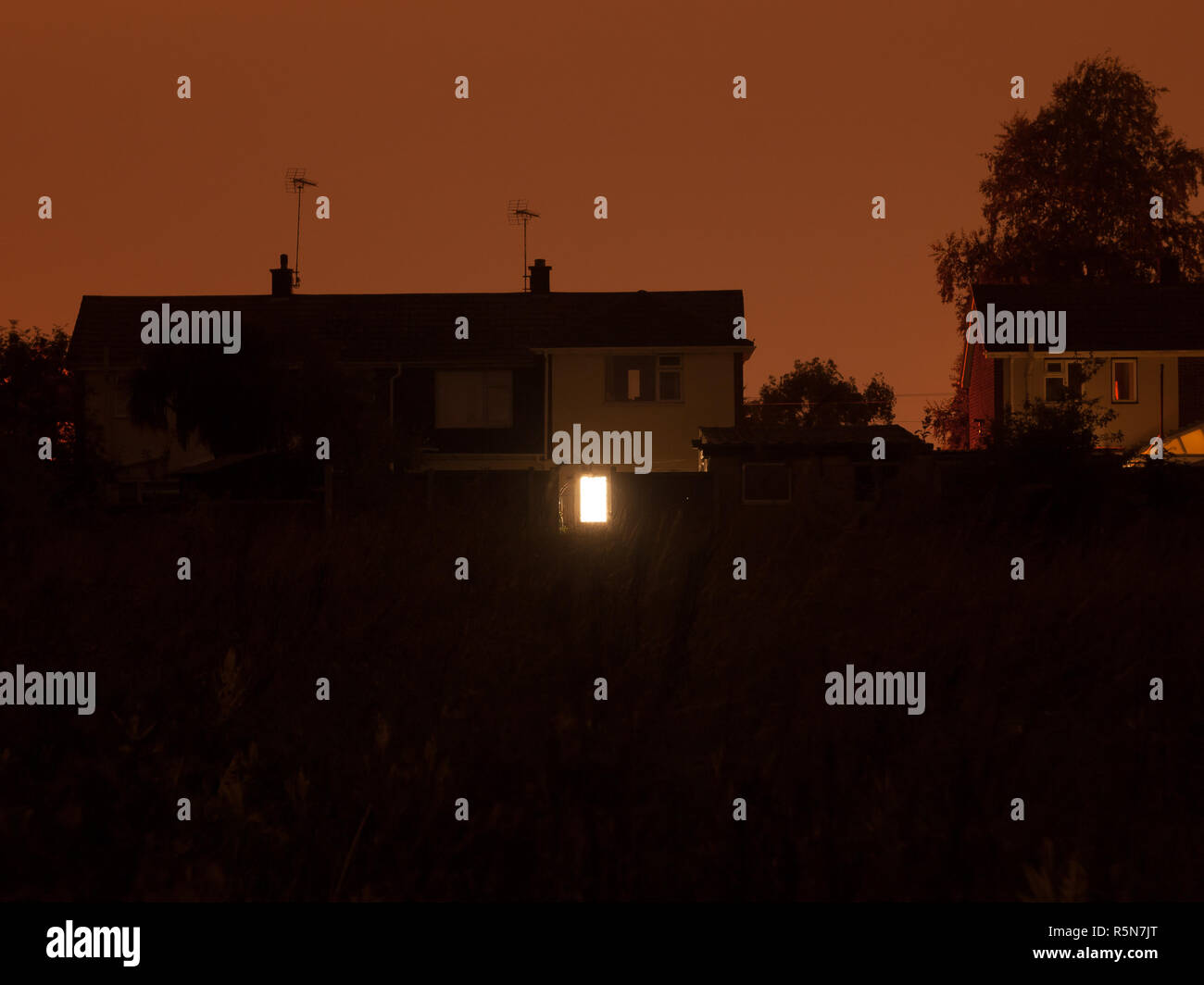 A single lit window downstairs at the back of a house during the dark ...