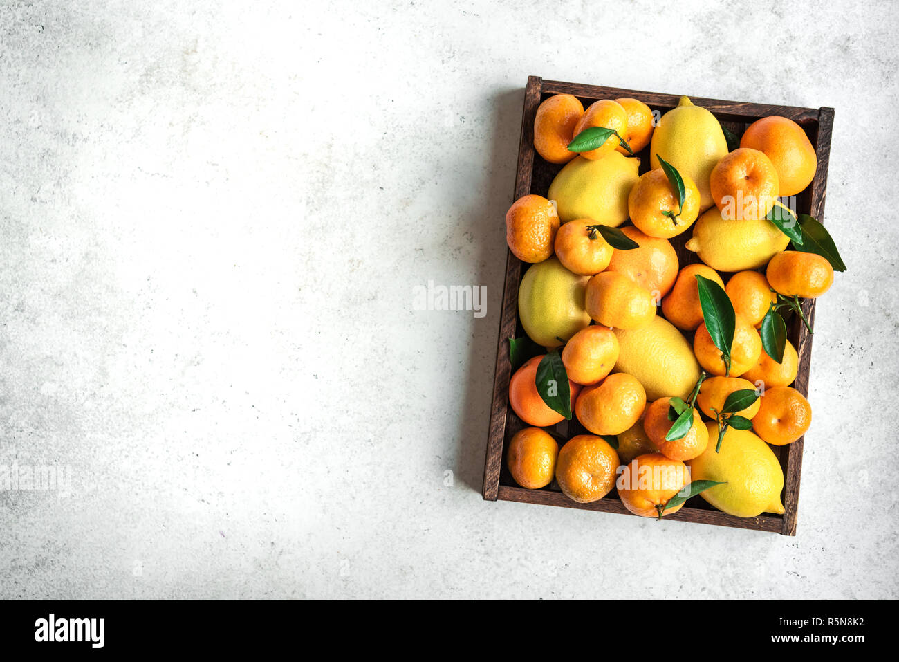 Various citrus fruits in box - lemons, tangerines, oranges with leaves ...