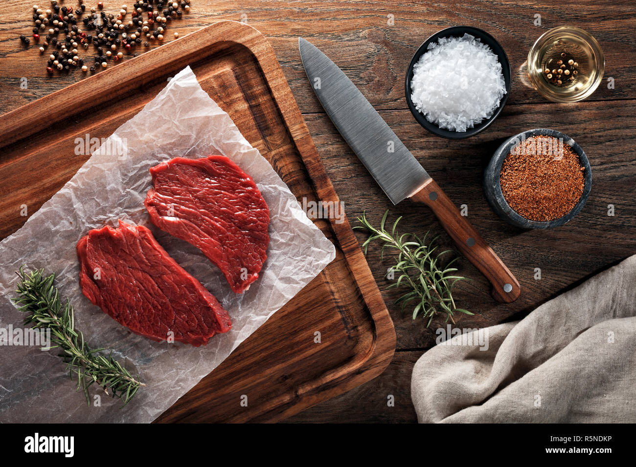 Slices of raw calf steak on white cooking paper and wooden cutting ...