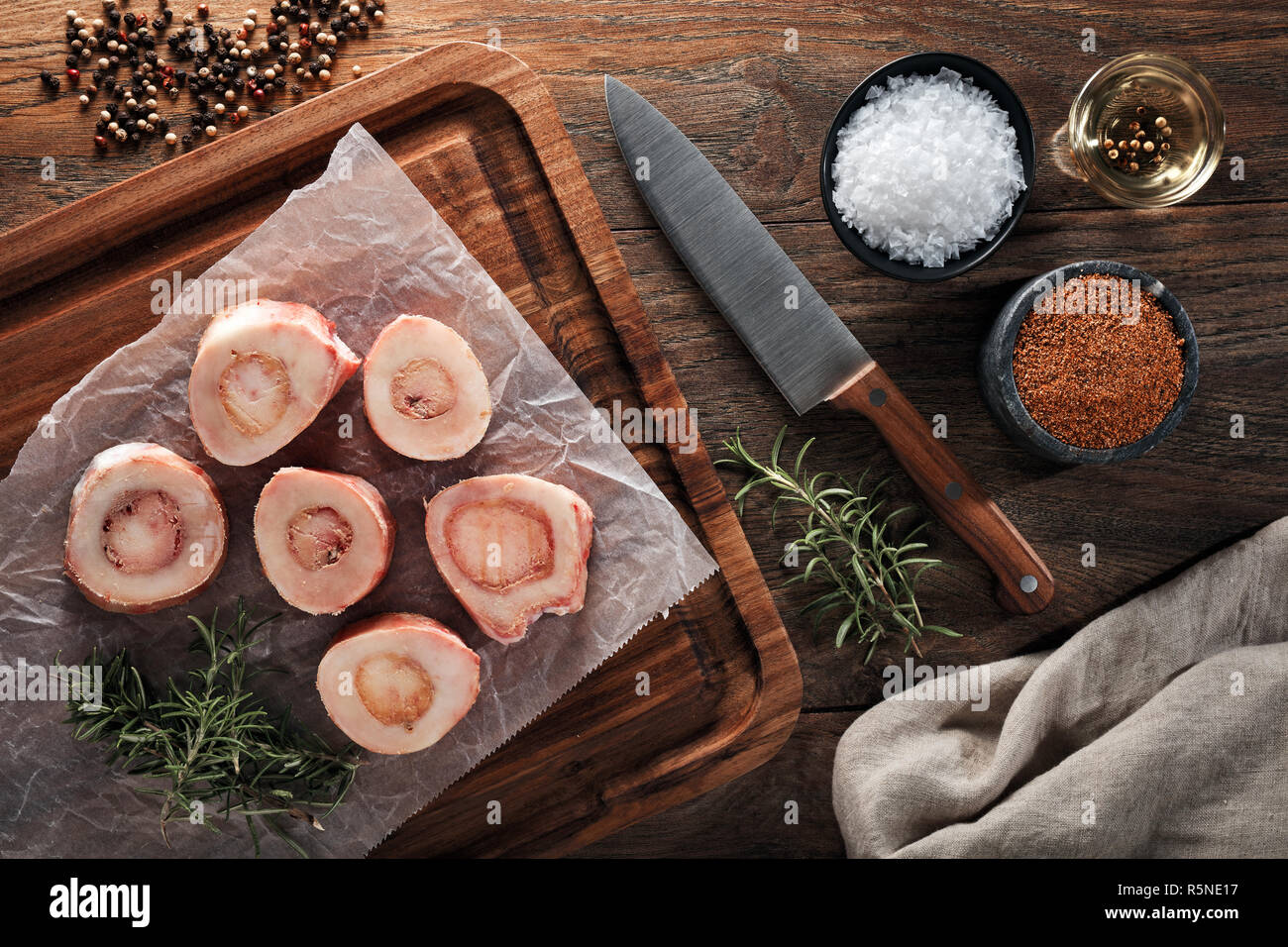 Raw calf bones on white cooking paper and wooden cutting board ...